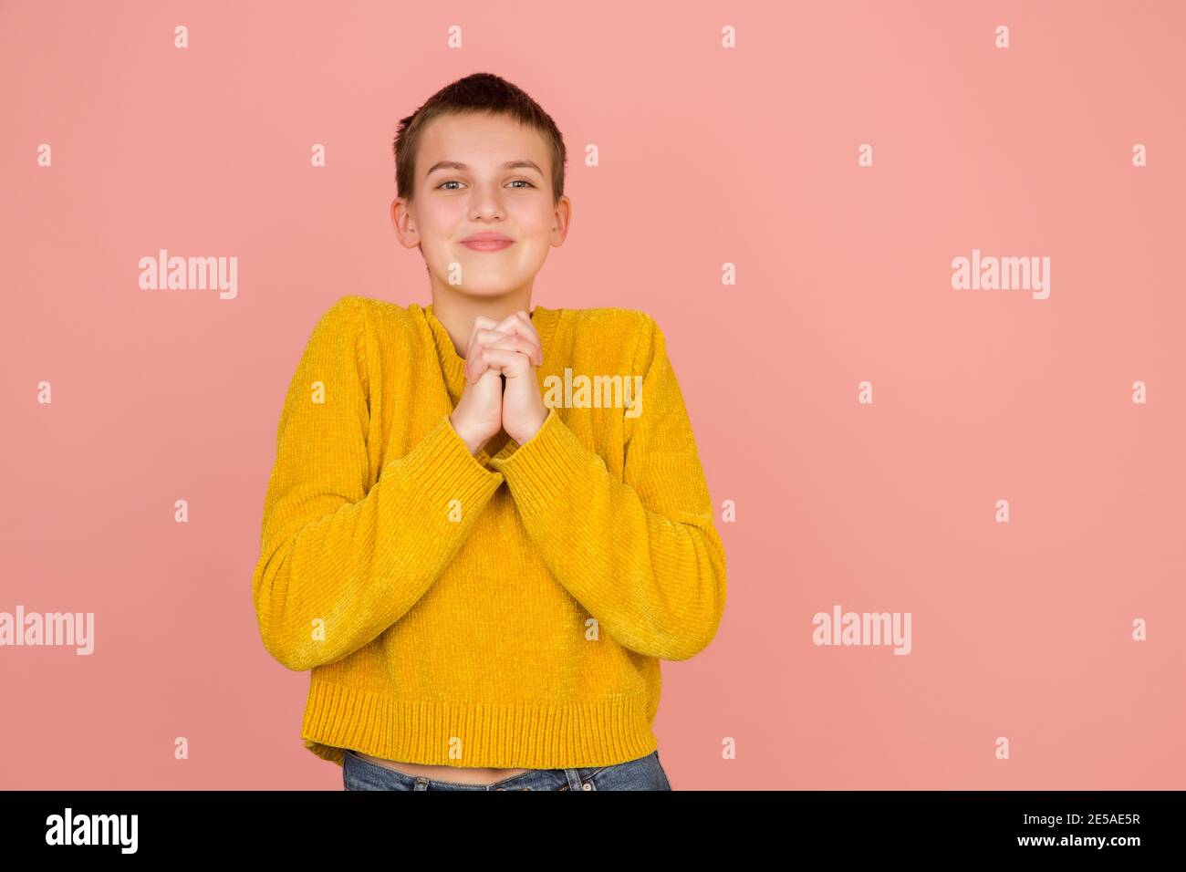 Hopeful asking. Caucasian girl's portrait on coral pink studio ...