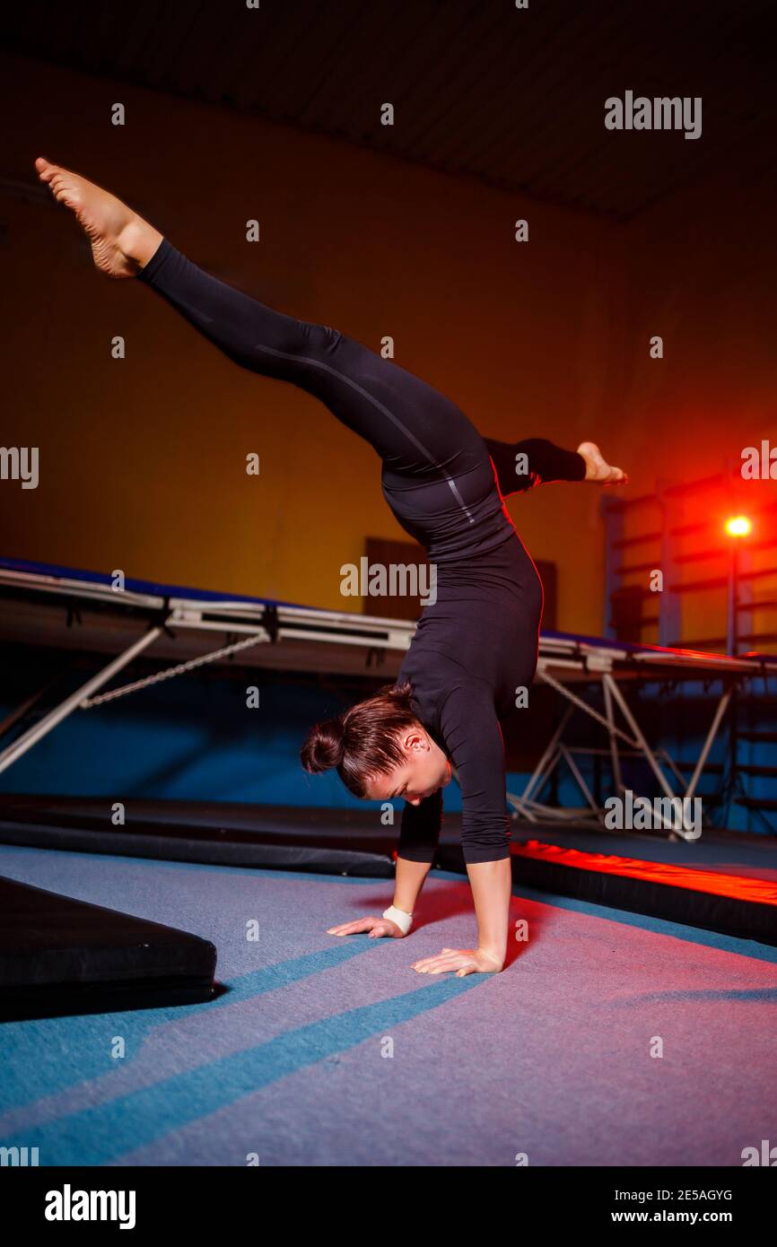 Young sportive girl doing handstand exercise. Young woman doing twine ...