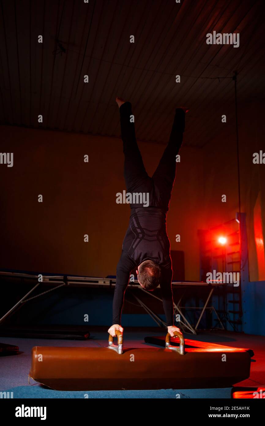 Young strong man doing handstand exercises. Male gymnast doing sports ...