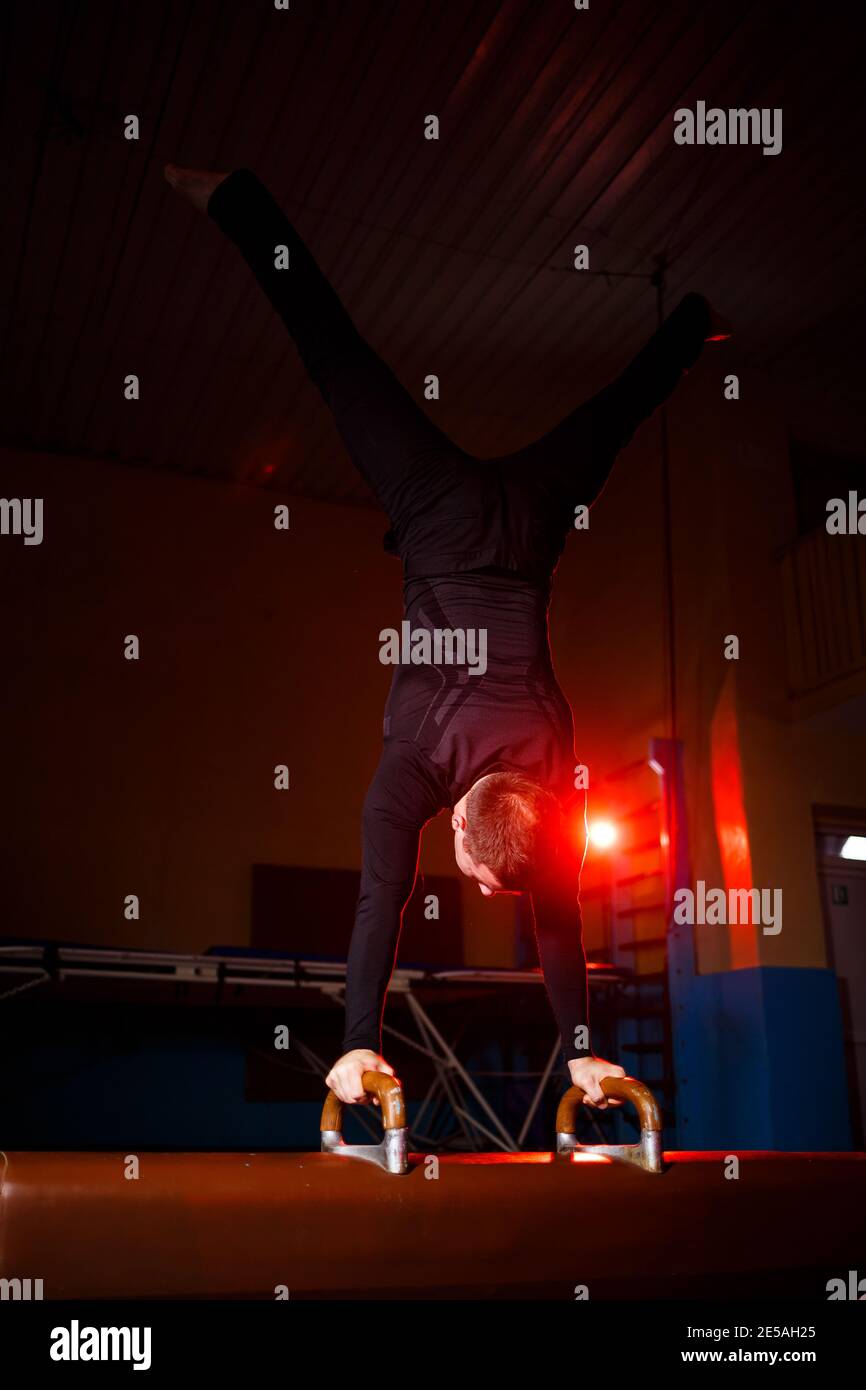 Young strong man doing handstand exercises. Male gymnast doing sports ...