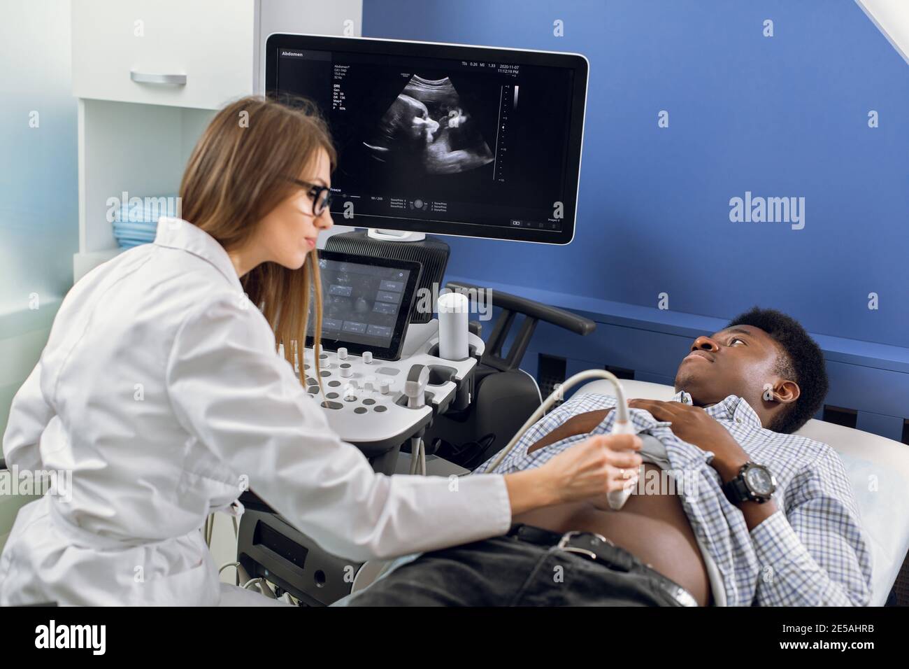 Young Caucasian woman doctor moving ultrasound transducer on African ...