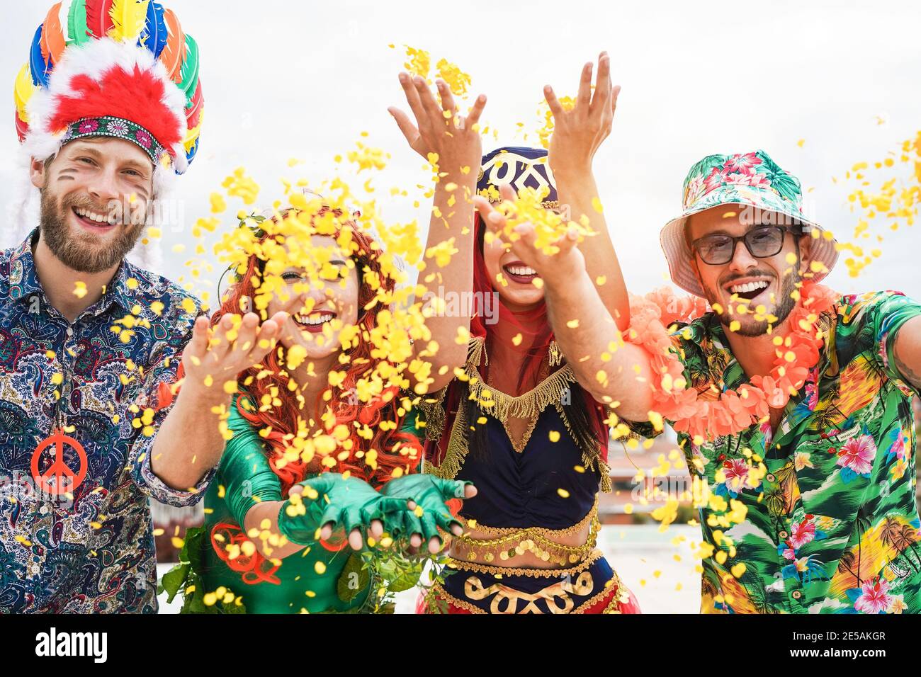Happy dressed people celebrating at carnival party throwing confetti ...