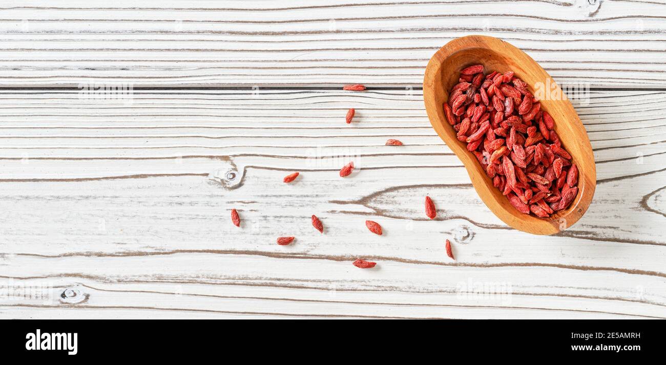 Dried goji aka. wolfberry seeds in wooden bowl and spilled on white ...