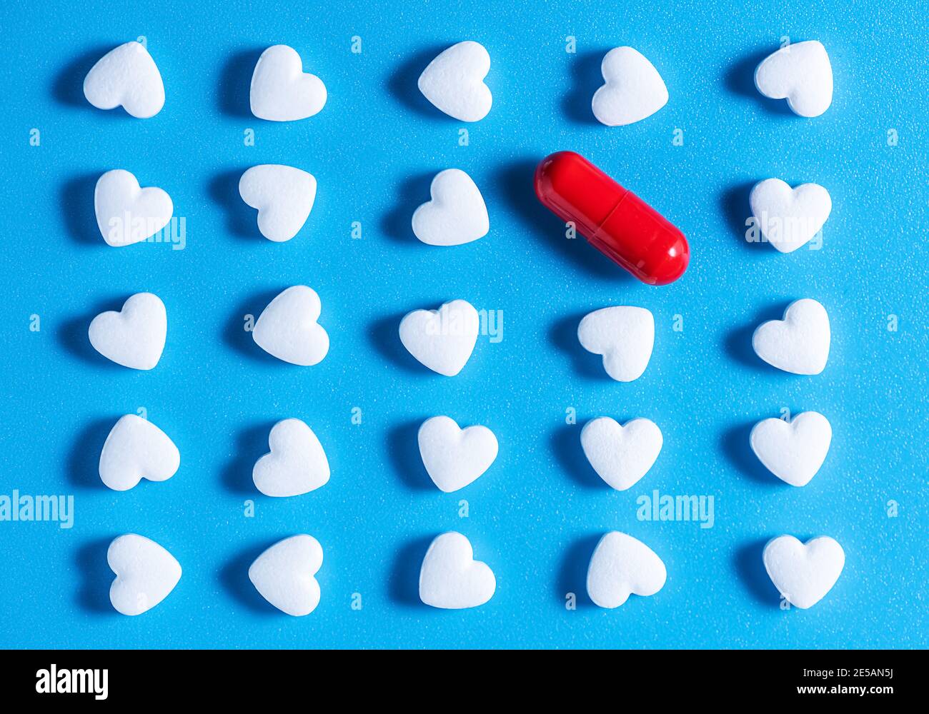 heart-shaped tablets and red pill. pattern on blue background. medicine ...