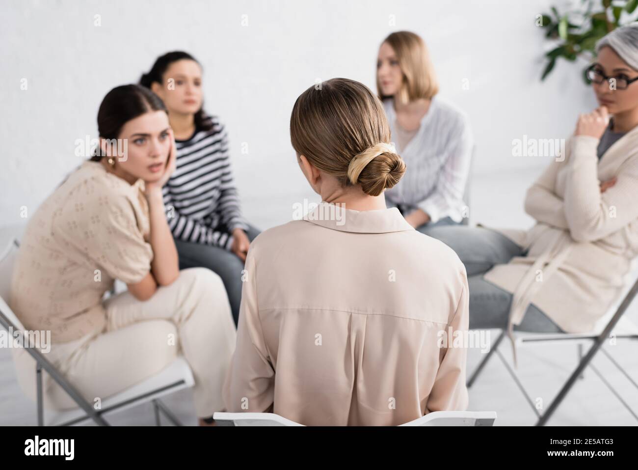 back view of woman sitting on chair near multicultural female group ...