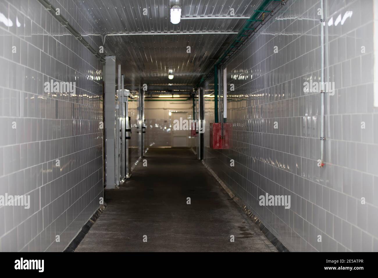 An empty corridor of a factory or workshop is faced with tiles and ...