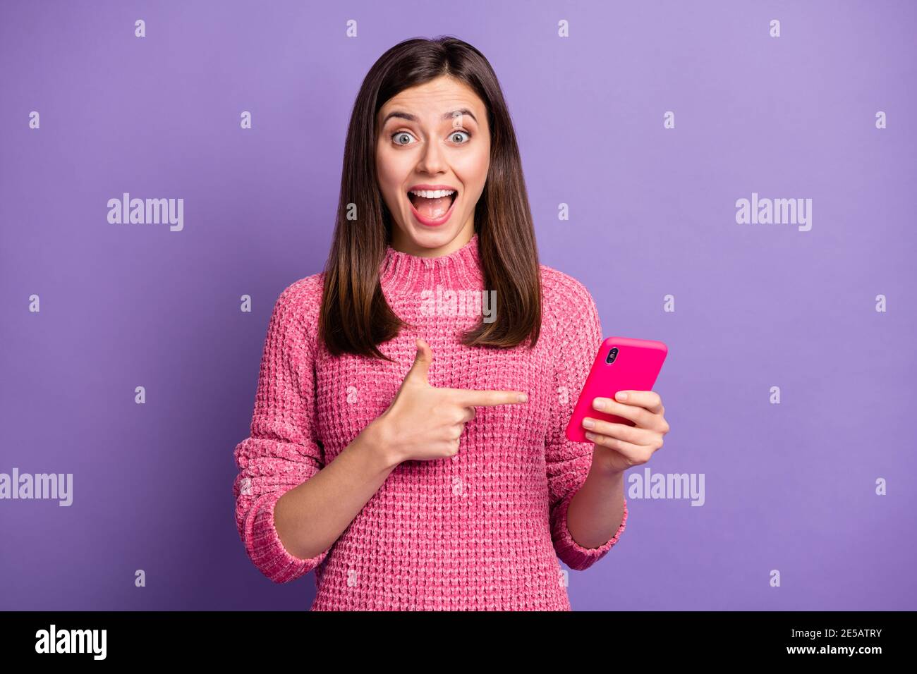 Photo portrait of amazed female brunette pointing finger cellphone ...