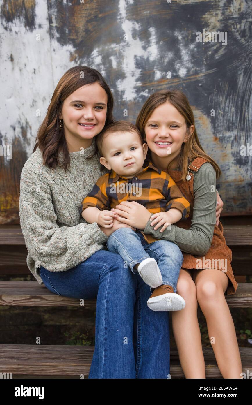 Two sisters and a little baby brother sitting on steps outside for a ...