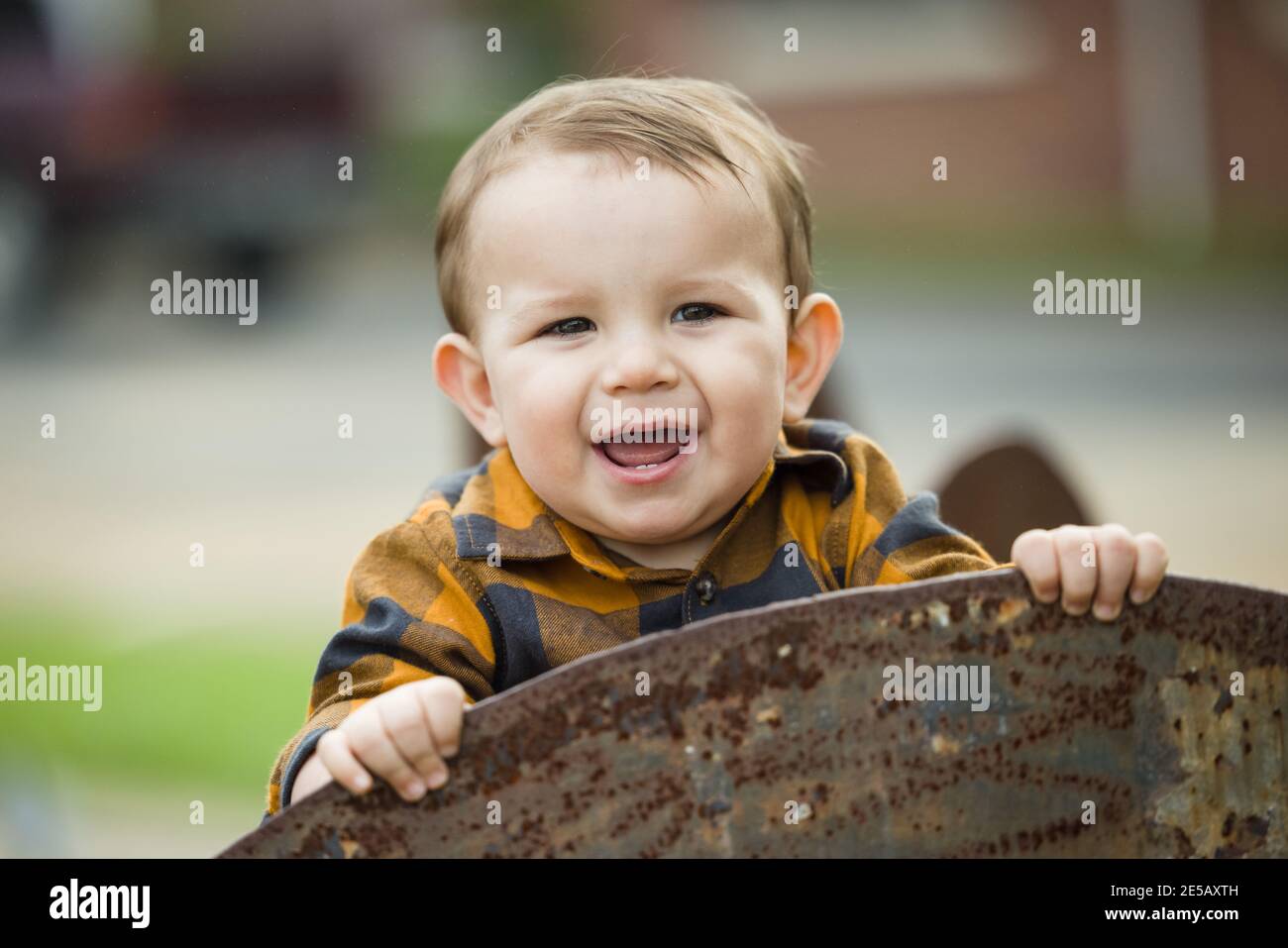 A baby boy hiding behind part of a metal sculpture and playing peek-a ...