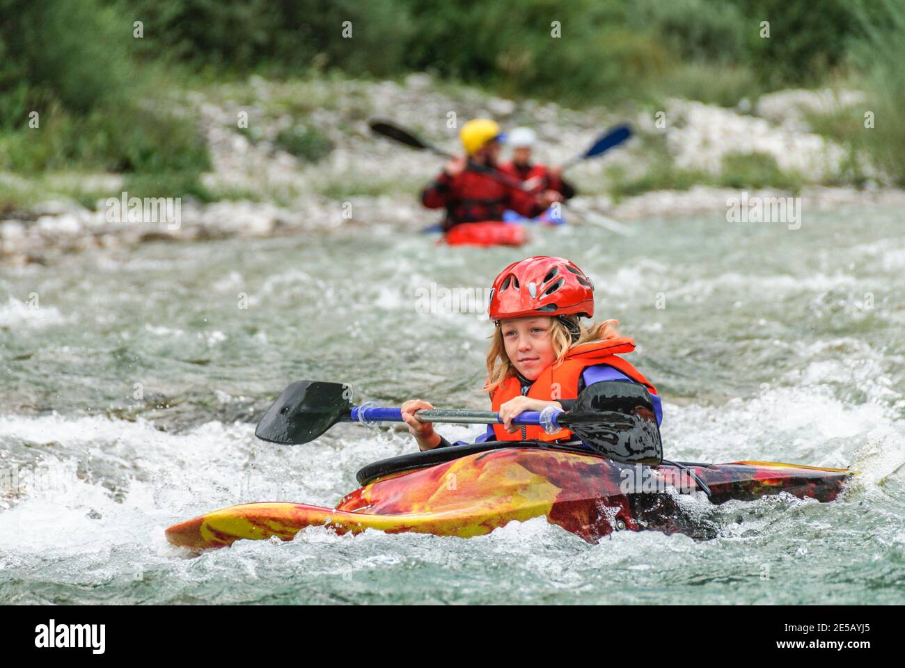 Courageous little girl paddling in kayak on alpine river Stock Photo ...