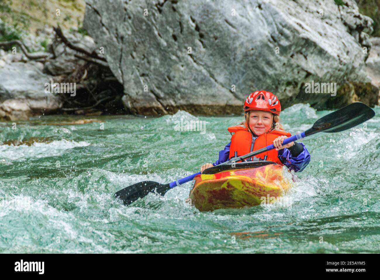 Courageous little girl paddling in kayak on alpine river Stock Photo ...