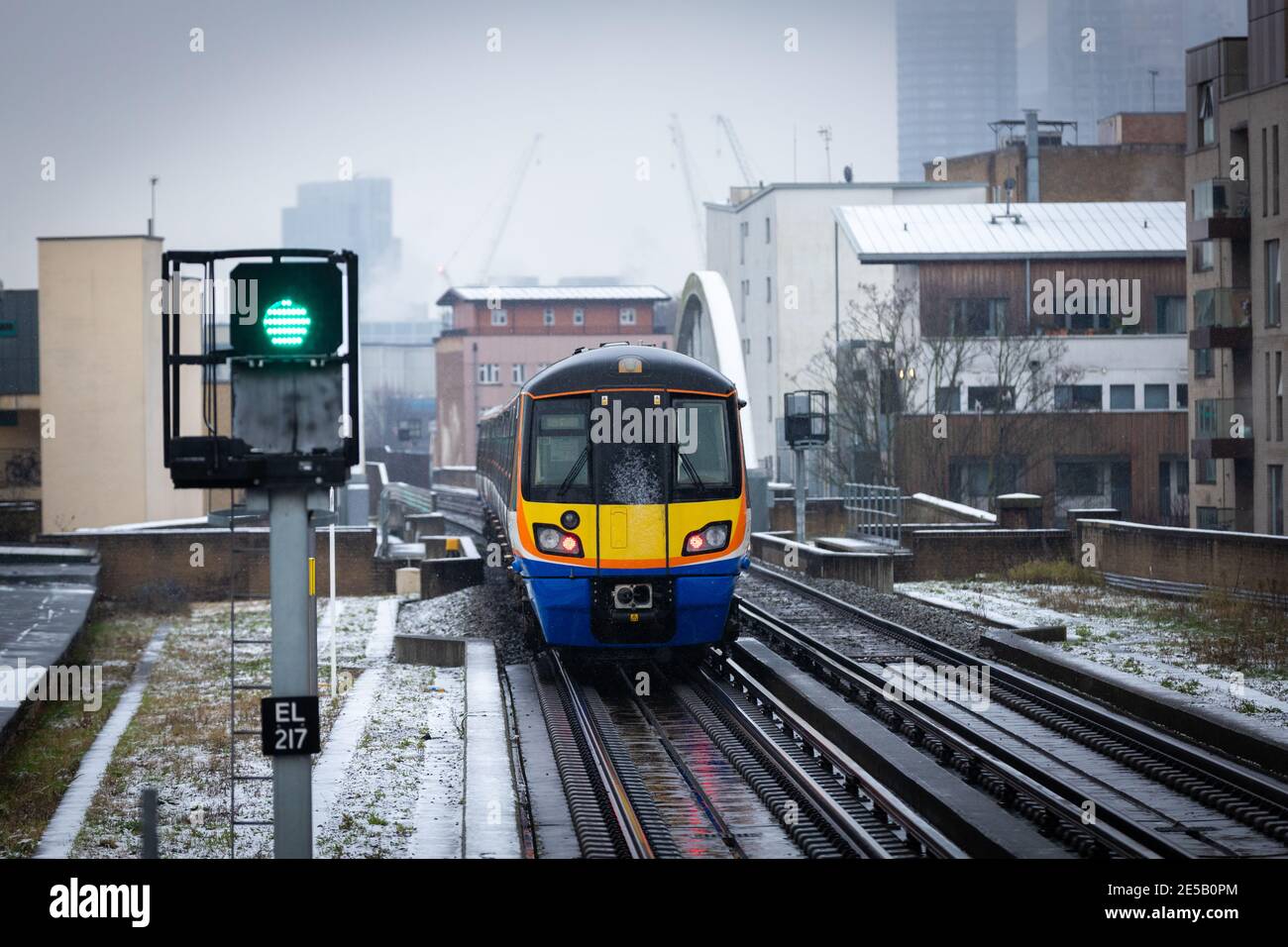 A Overground train approaches Haggerston station on a cold snowy day ...