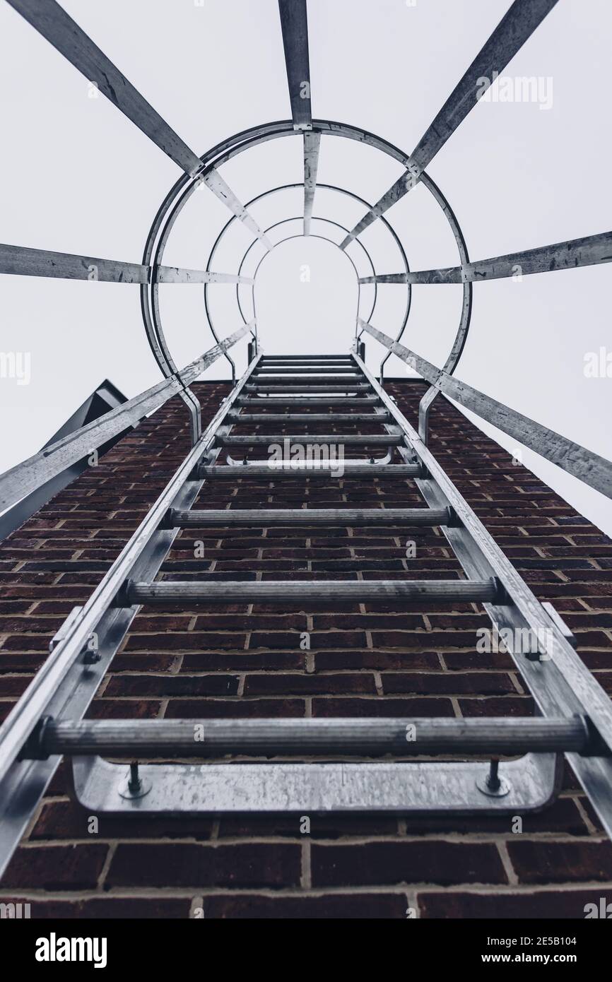 Fixed ladder going up the side of a brick building fitted with a steel ...
