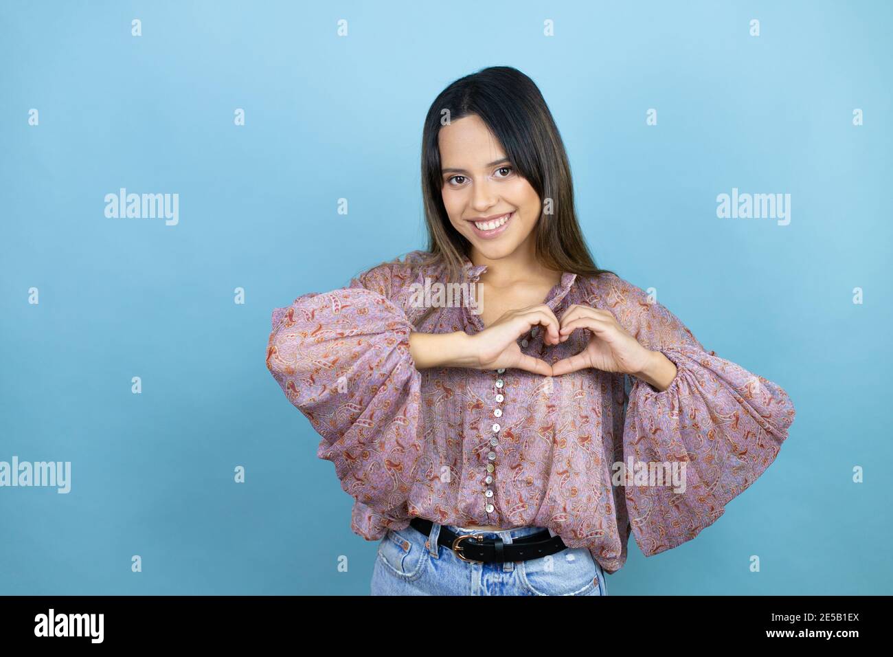 Beautiful latin woman wearing a pink shirt over blue isolated ...