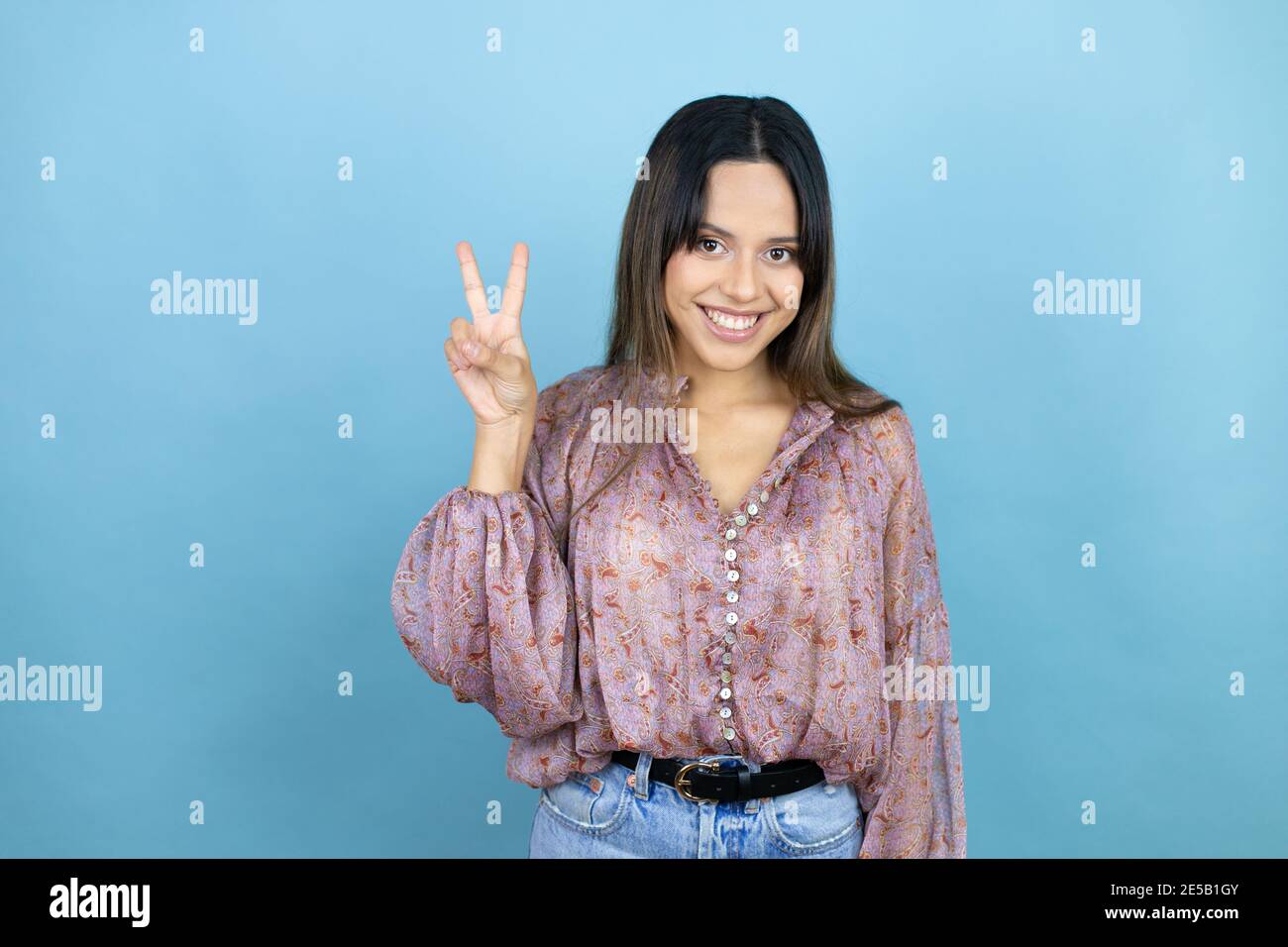 Beautiful latin woman wearing a pink shirt over blue isolated ...