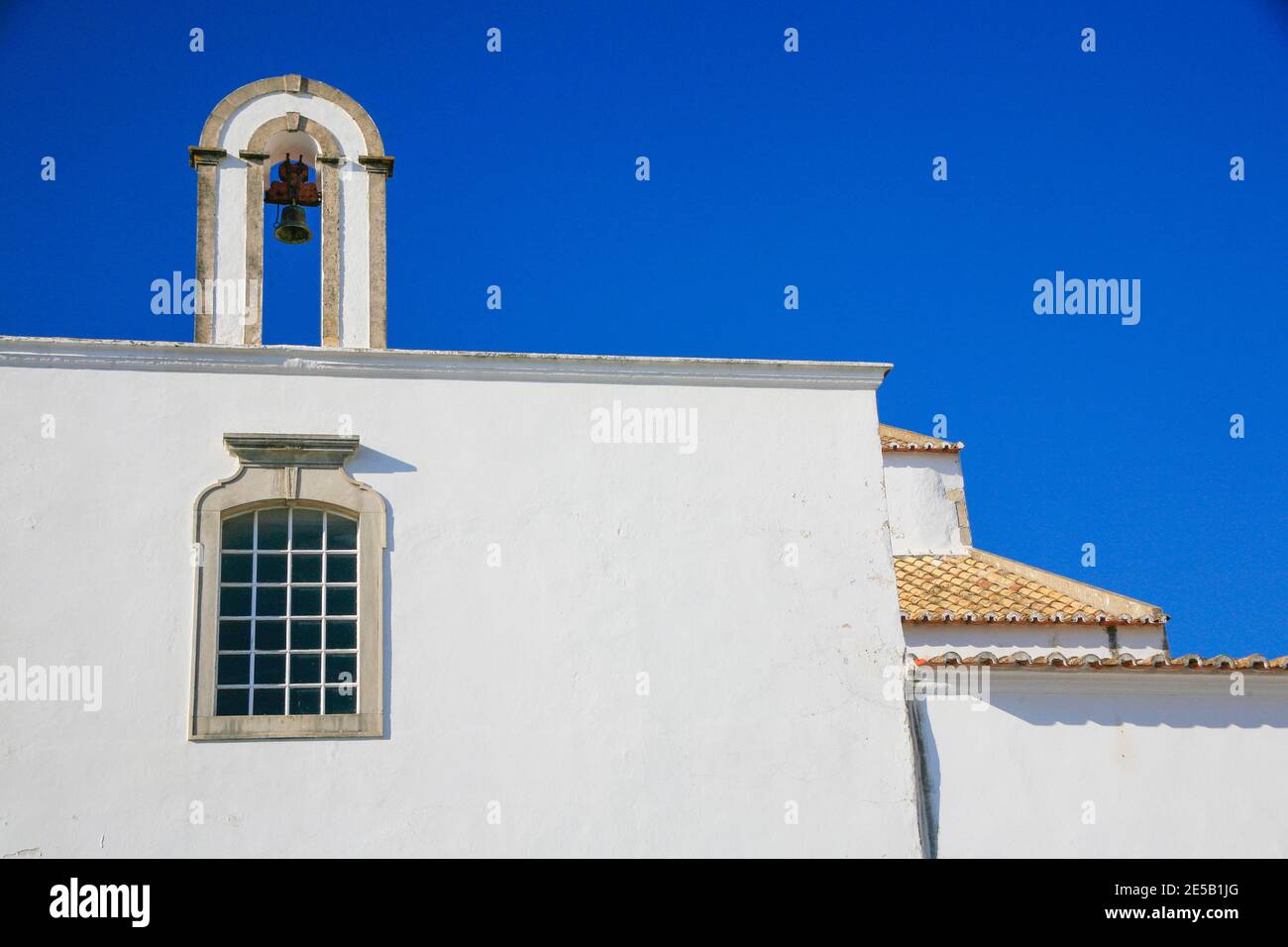 Typical Portuguese building, white wall, blue sky, with arched bell ...
