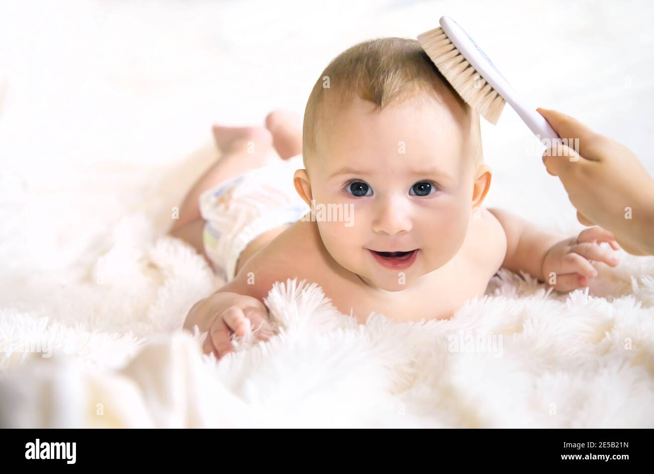 The mother is combing the little baby's hair. Selective focus. People ...