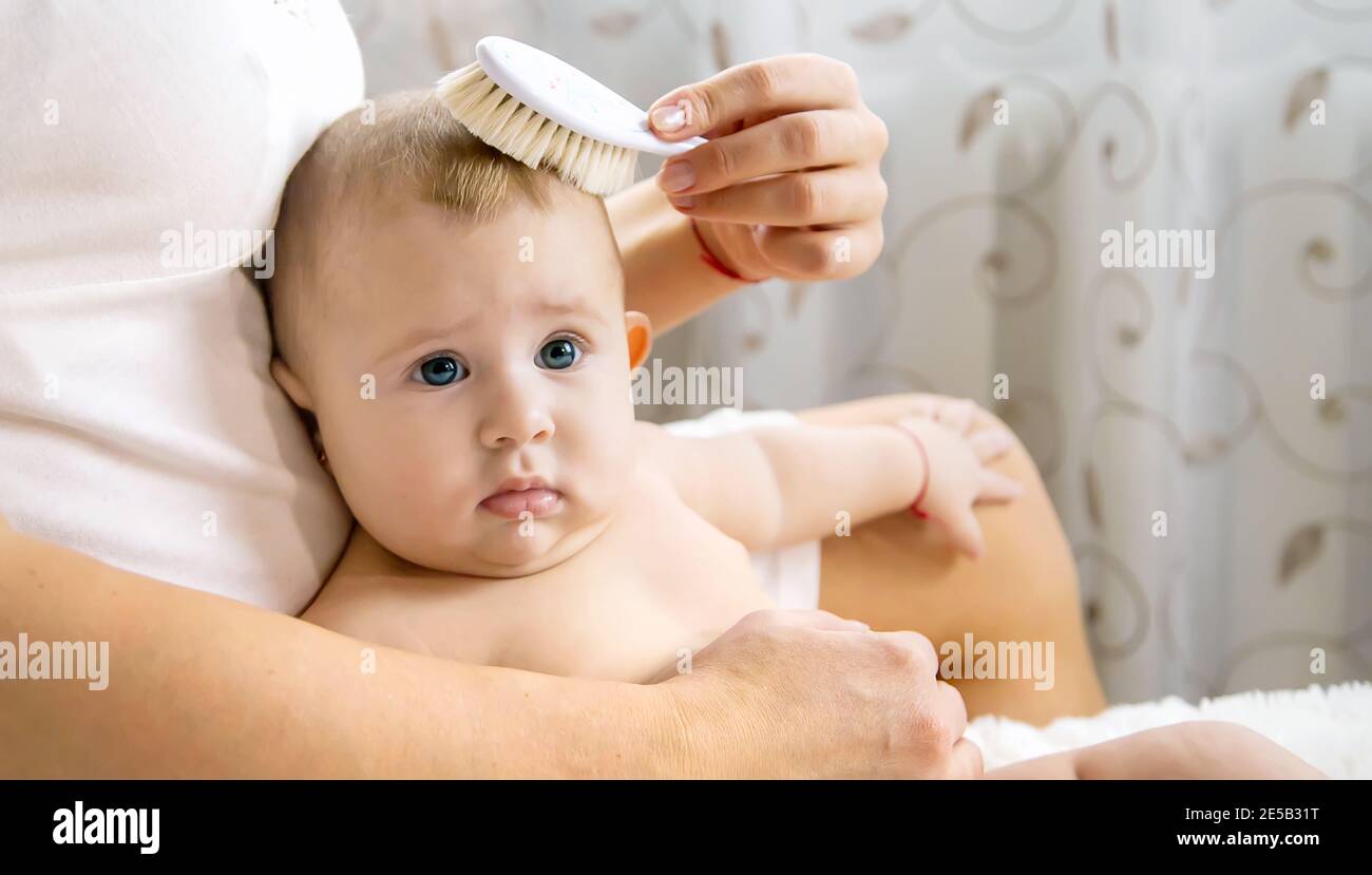 The mother is combing the little baby's hair. Selective focus. People ...