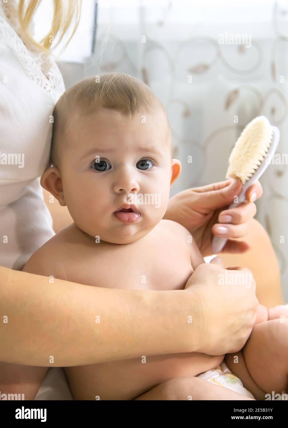 The mother is combing the little baby's hair. Selective focus. People ...