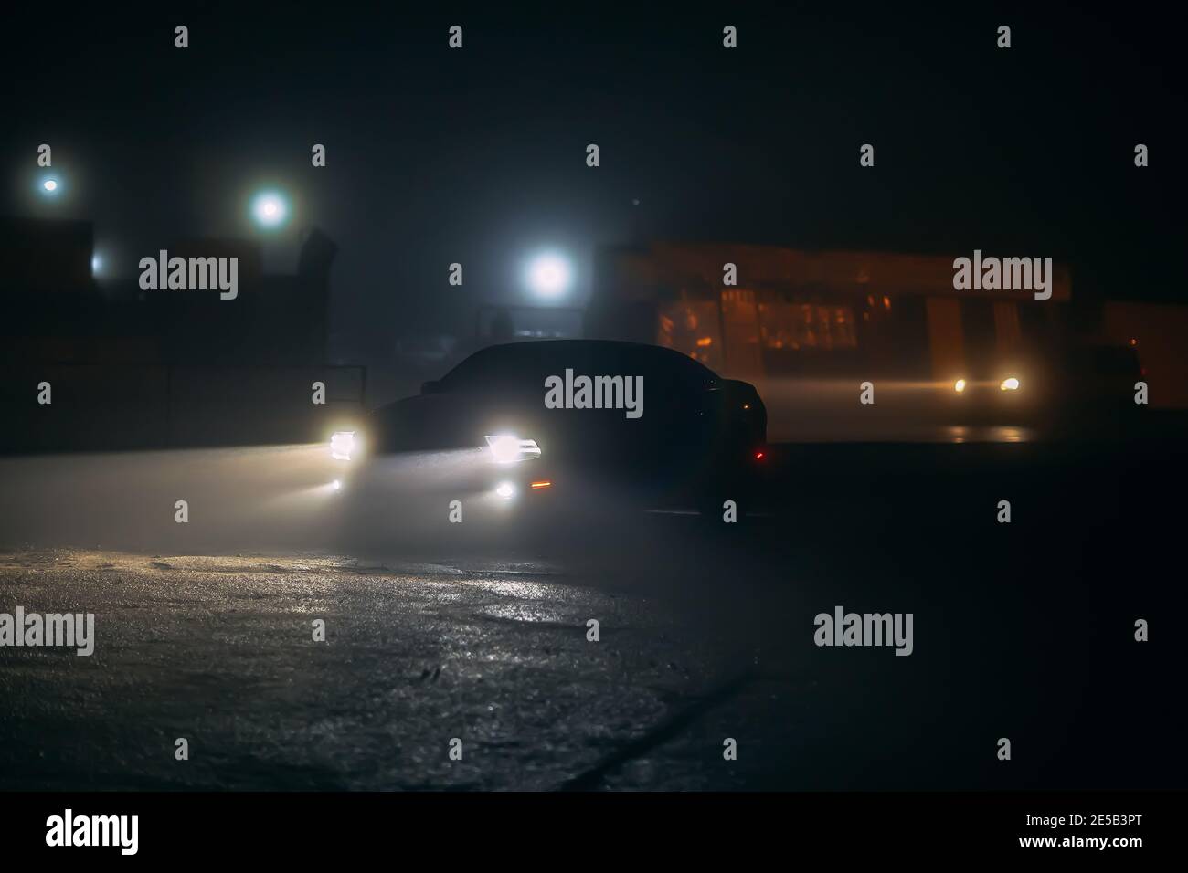 Sport car stands with in the shadows with glowing headlights at foggy ...