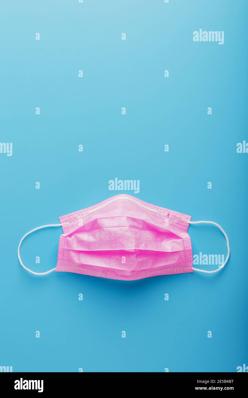Pink medical mask on a blue background vertical composition free space ...