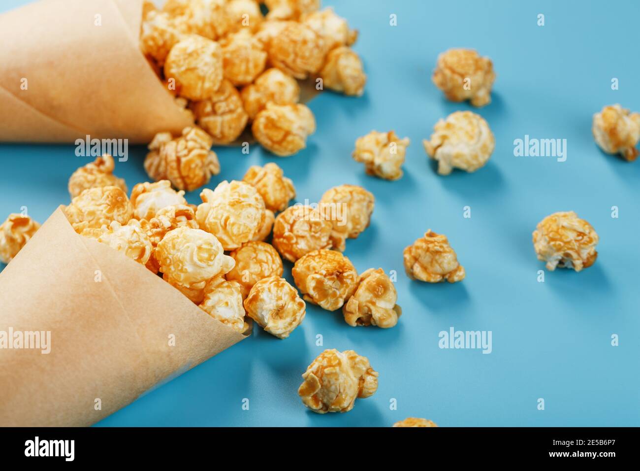 Caramel popcorn in a paper envelope on a blue background. Delicious ...