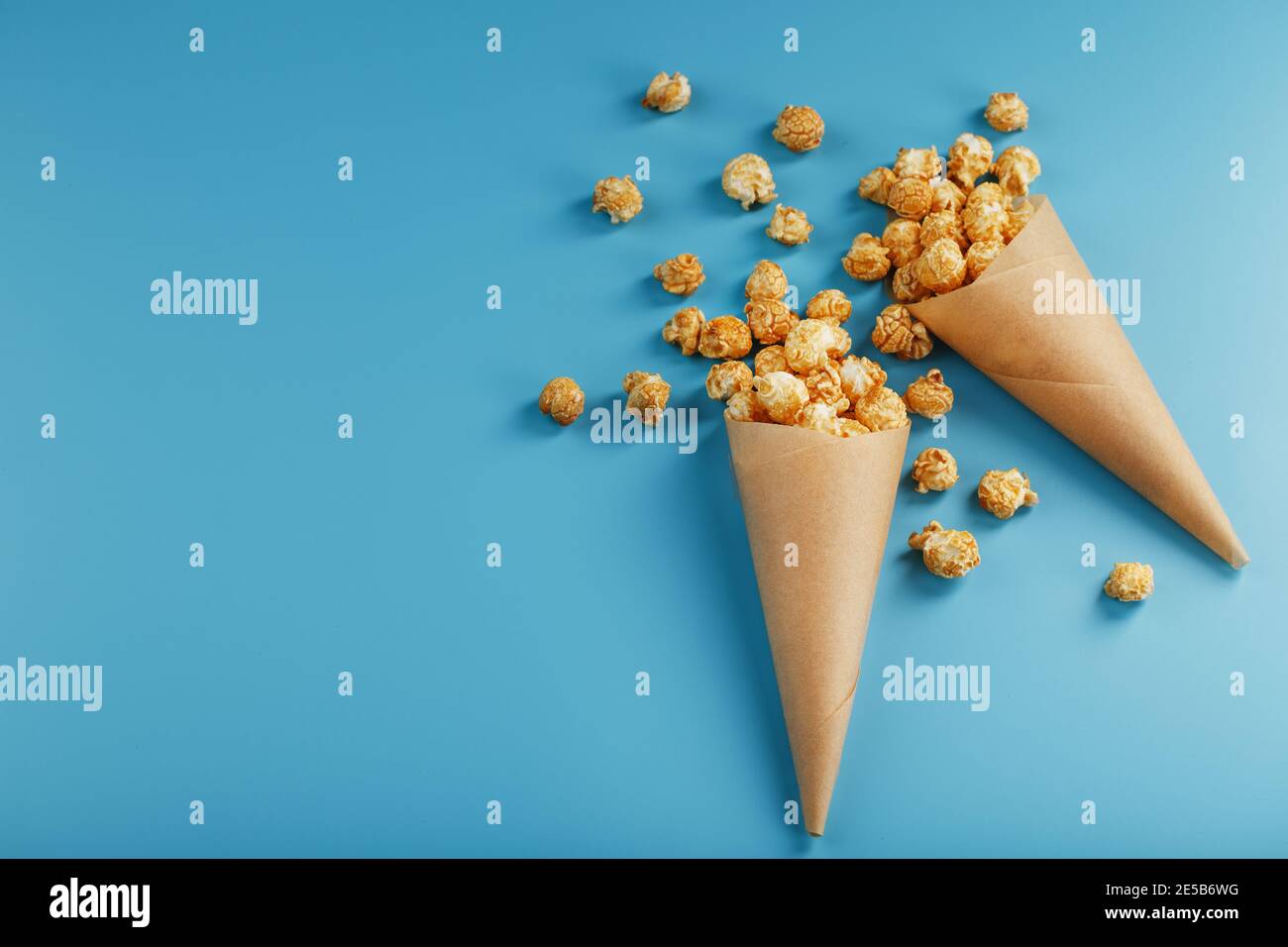 Caramel popcorn in a paper envelope on a blue background. Delicious ...