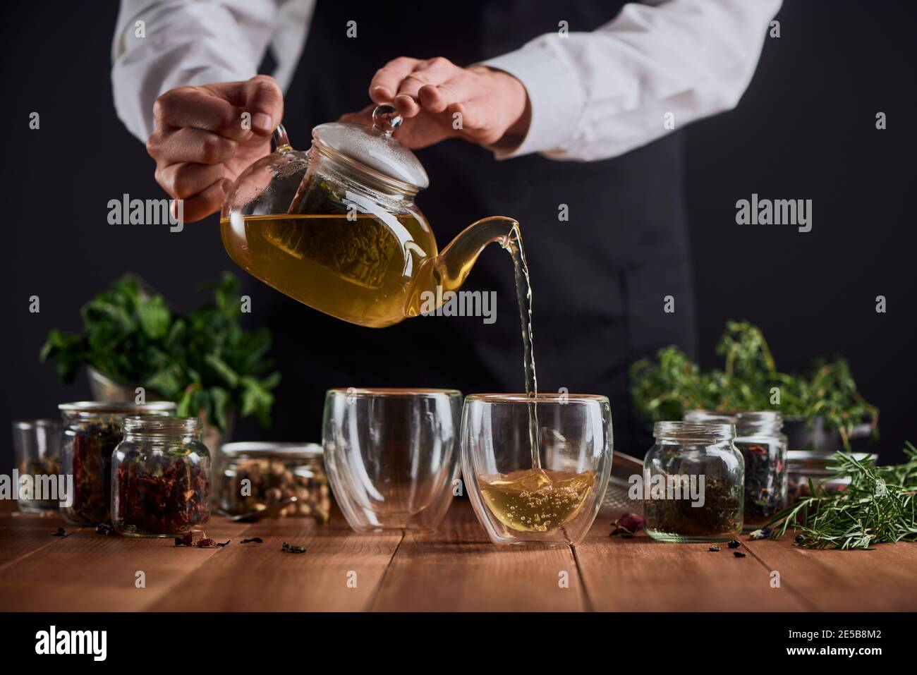 Tea master pouring hot tea from a pot into two glass cups Stock Photo ...