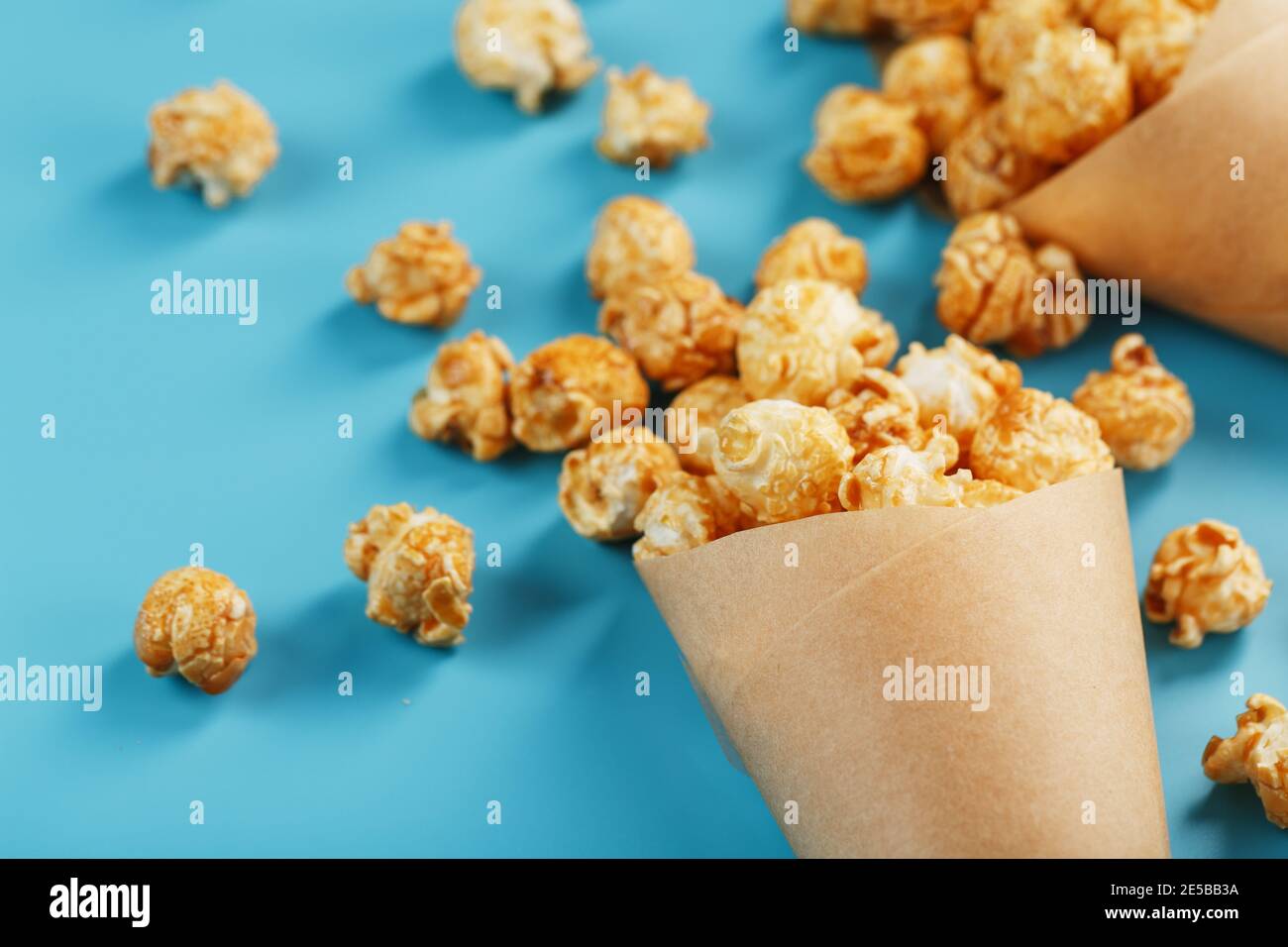 Caramel popcorn in a paper envelope on a blue background. Delicious ...