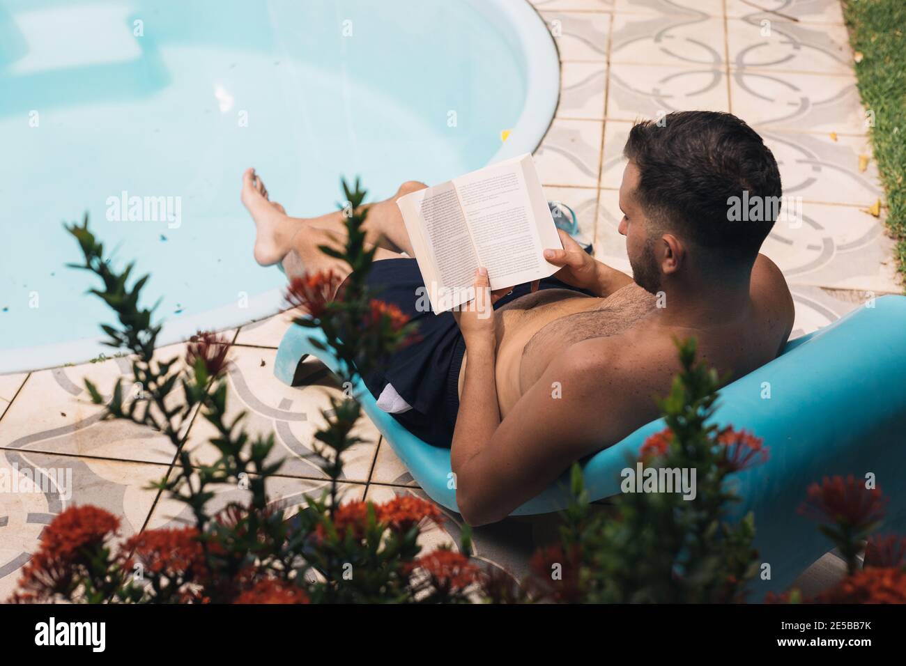 man in a pool reading by a pool Stock Photo - Alamy
