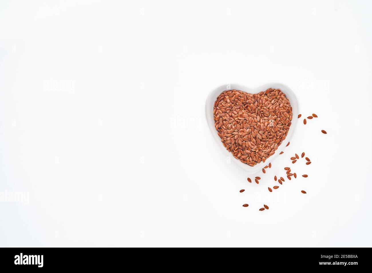 Flax seeds in bowl of the shape of heart isolated on white background, top view Stock Photo - Alamy