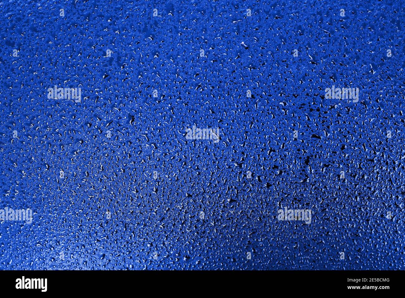 Small drops of water or condensation on a rich blue surface. Abstract ...