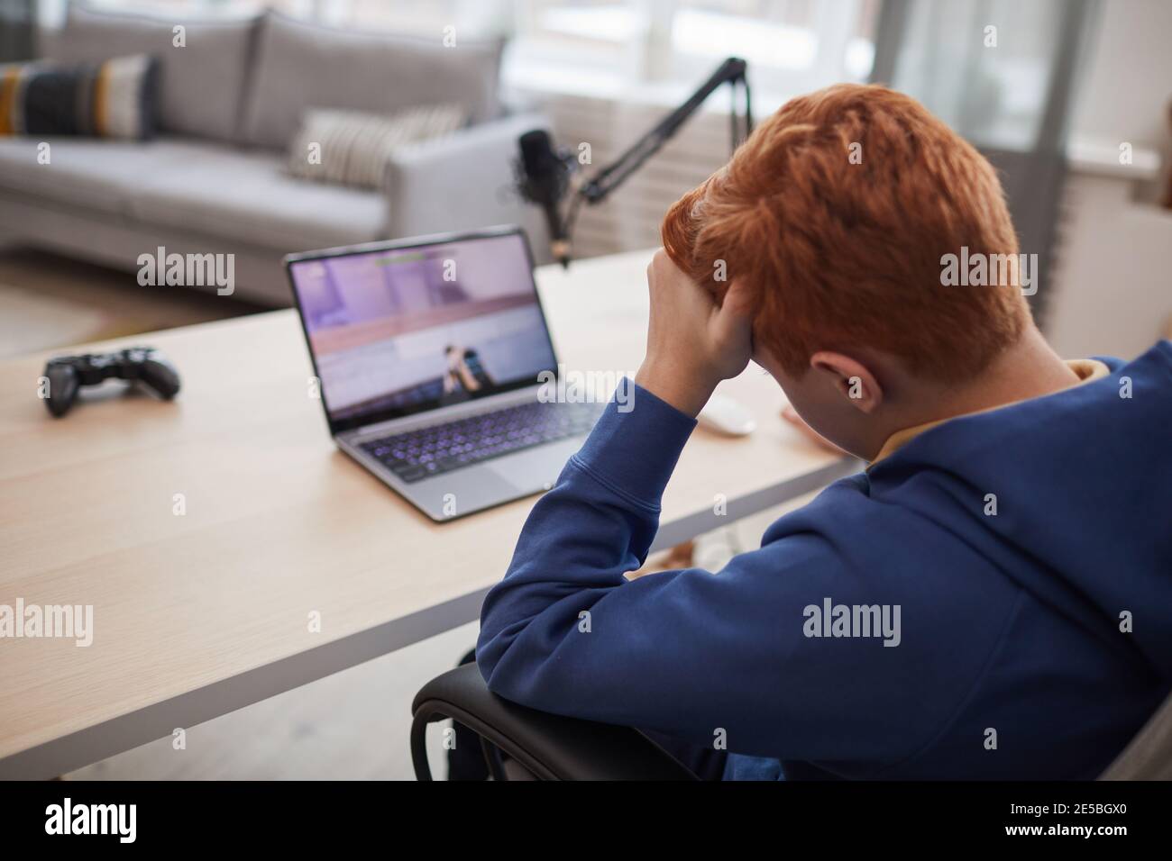 Back view portrait of distressed teenage boy suffering defeat or ...