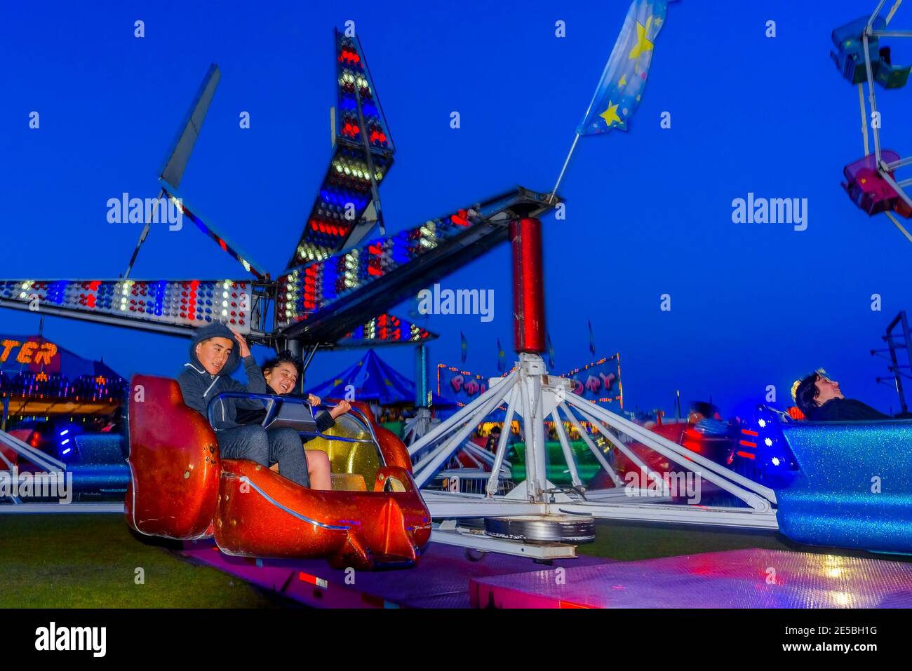 Boys enjoying Carnival Fun Fair Ride Stock Photo - Alamy