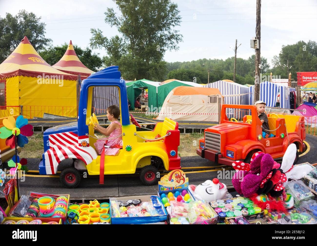 Children ride carousel cars in the playground on a summer day during ...