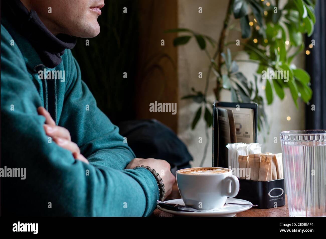 Young man in a cafe, leaning on his elbows with a cup of coffee in ...