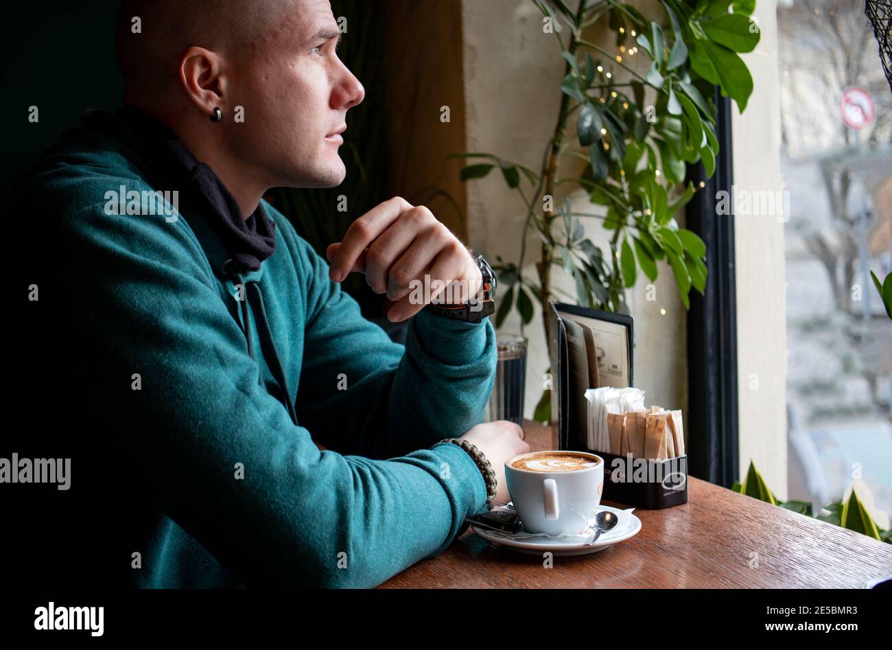 Young man in a cafe, leaning on his elbows with a cup of coffee in ...