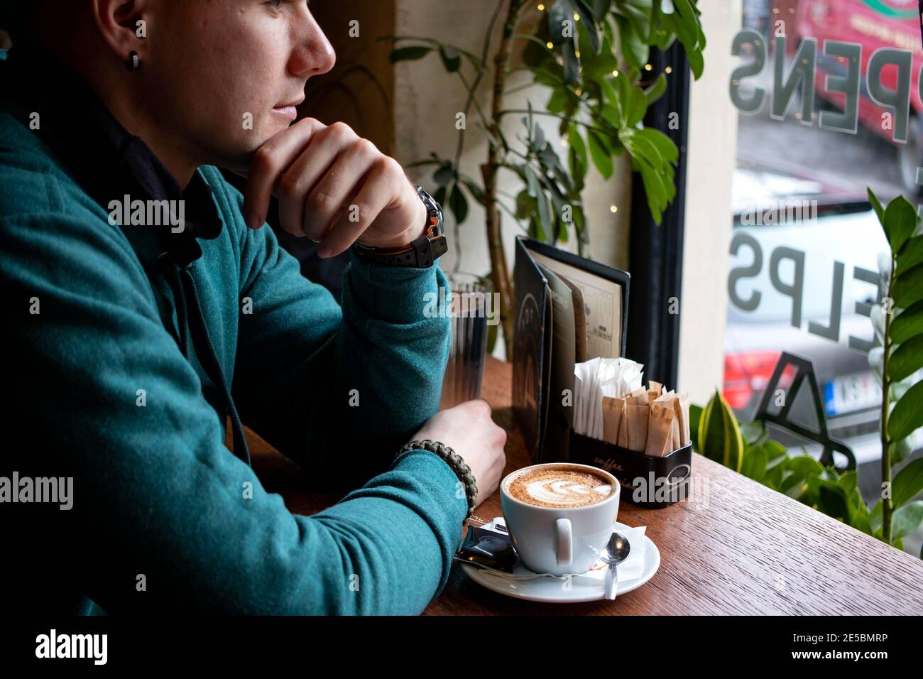 Young man in a cafe, leaning on his elbows with a cup of coffee in ...