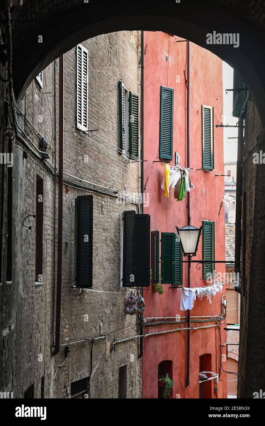 Glimpse of a narrow alley under an arch with washing lines hanging ...