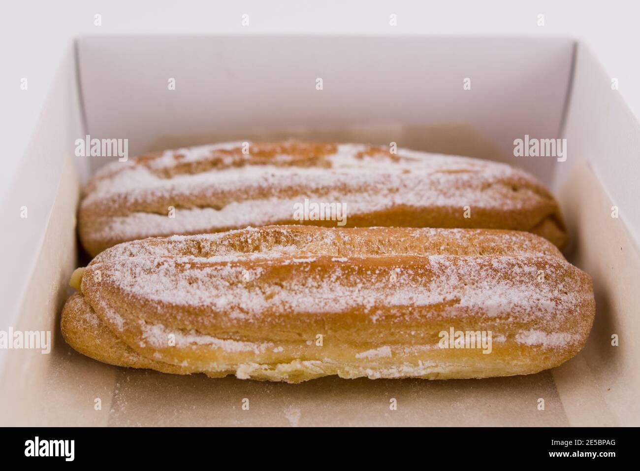 a delicious French eclairs in a box with powdered sugar Stock Photo - Alamy