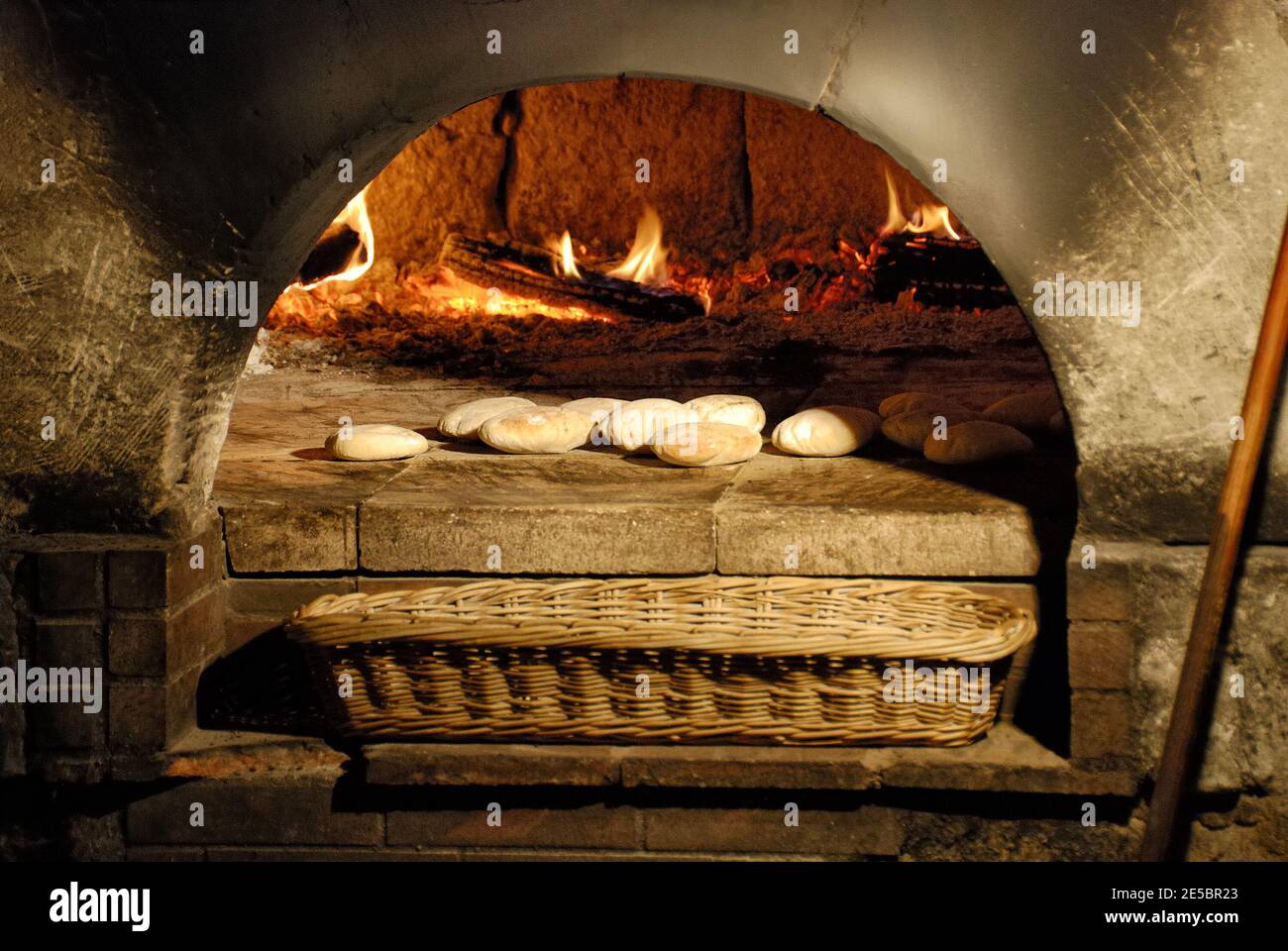 Traditional wood fired bread being placed into a super hot brick oven ...