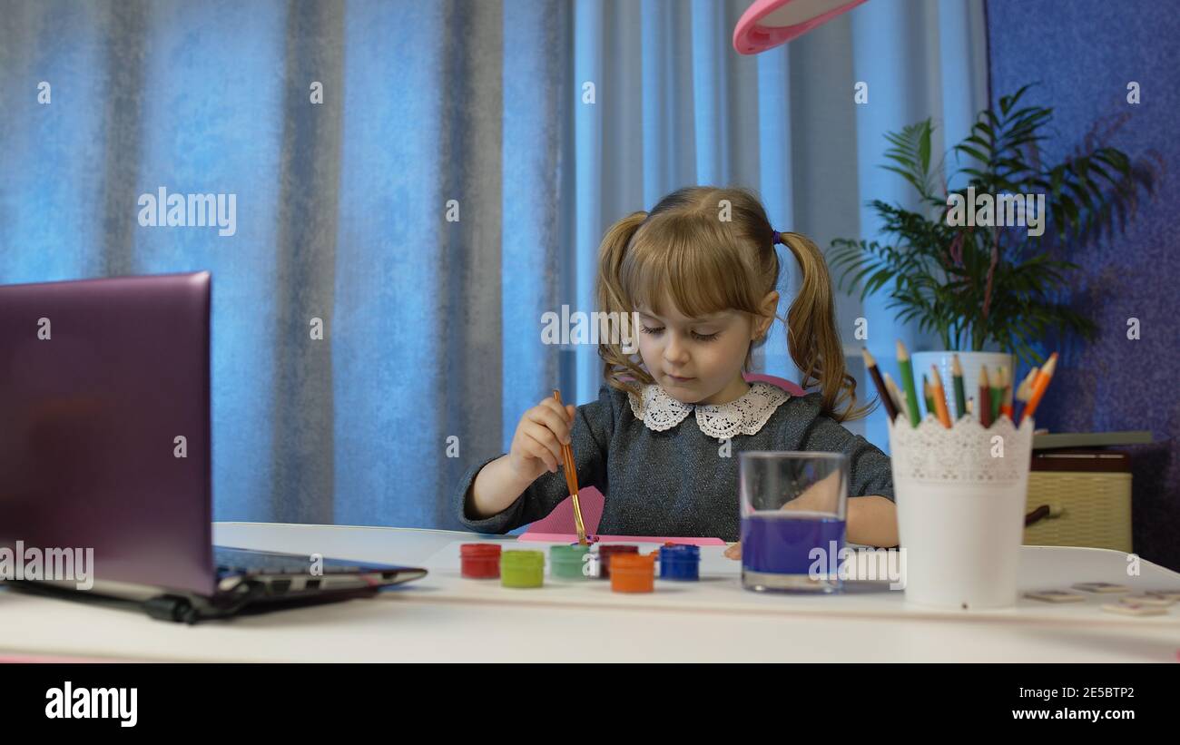 Child girl enthusiastically drawing with brushes and paints, using ...