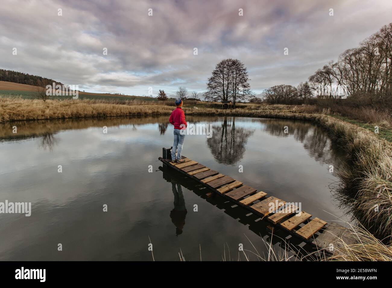 Woman watching reflections in pond during cold winter morning in the ...