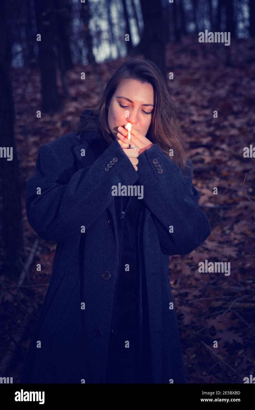 young brunette woman smoking cigarette in the forest in autumn Stock ...