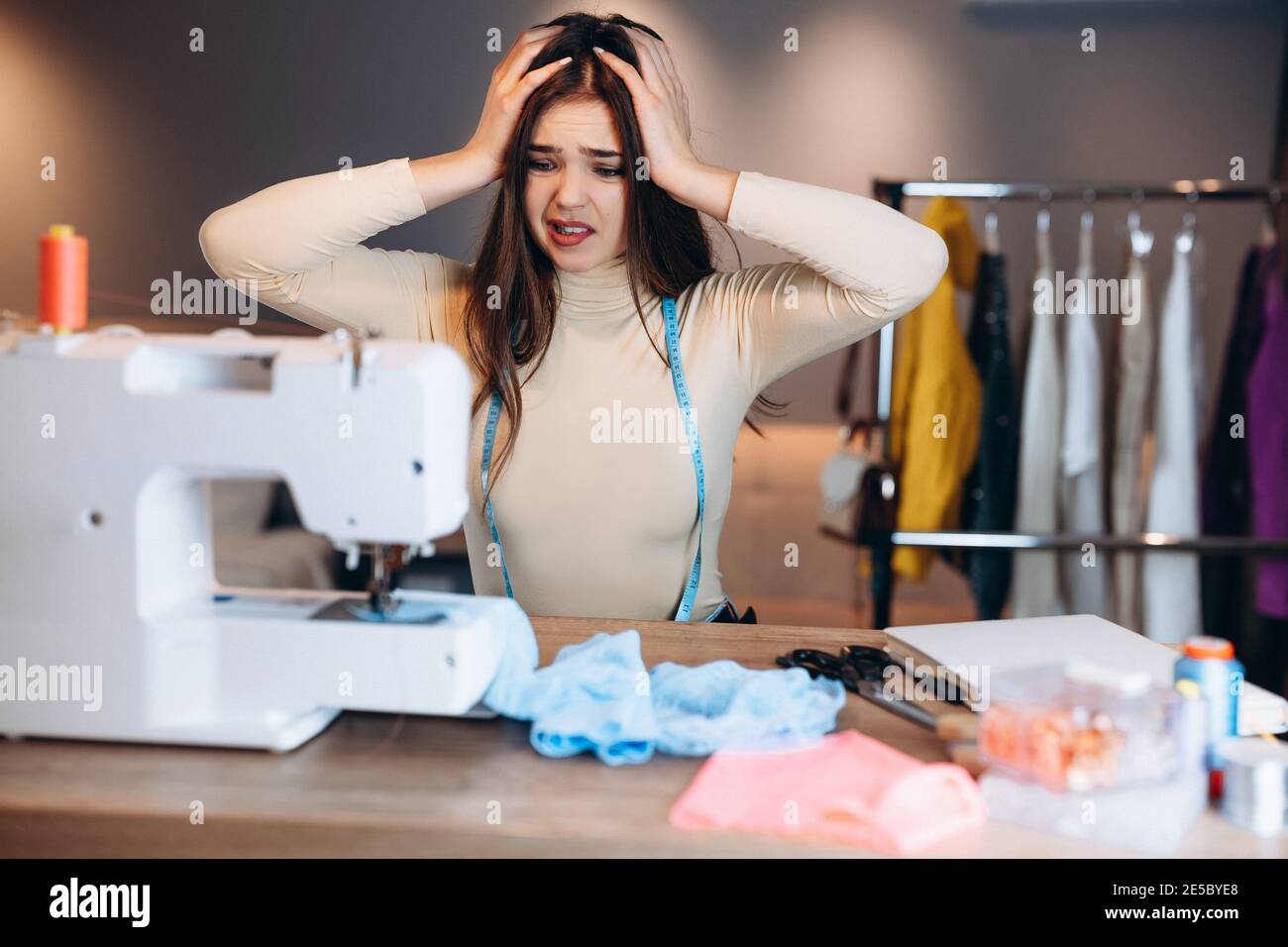 Young dressmaker woman sews clothes on sewing machine. Making mistakes ...