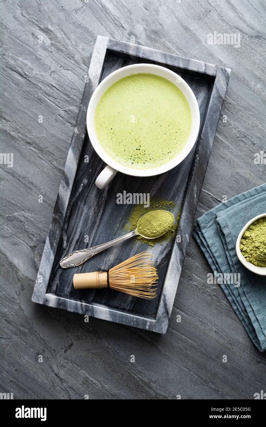 A cup of fresh frothy Matcha green tea decorated with bamboo whisk on a ...