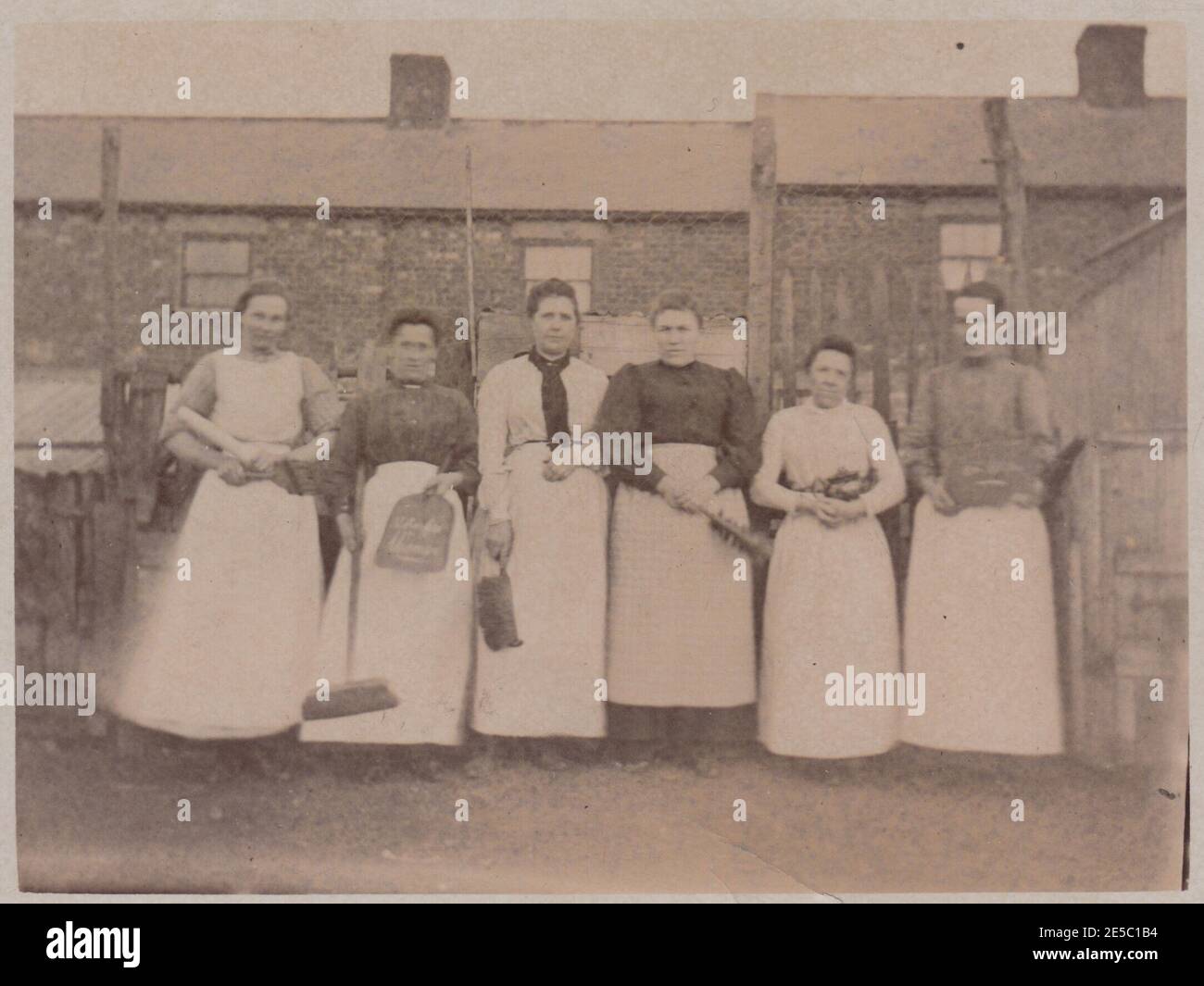 Group of servants standing at the back of a row of houses, carrying ...