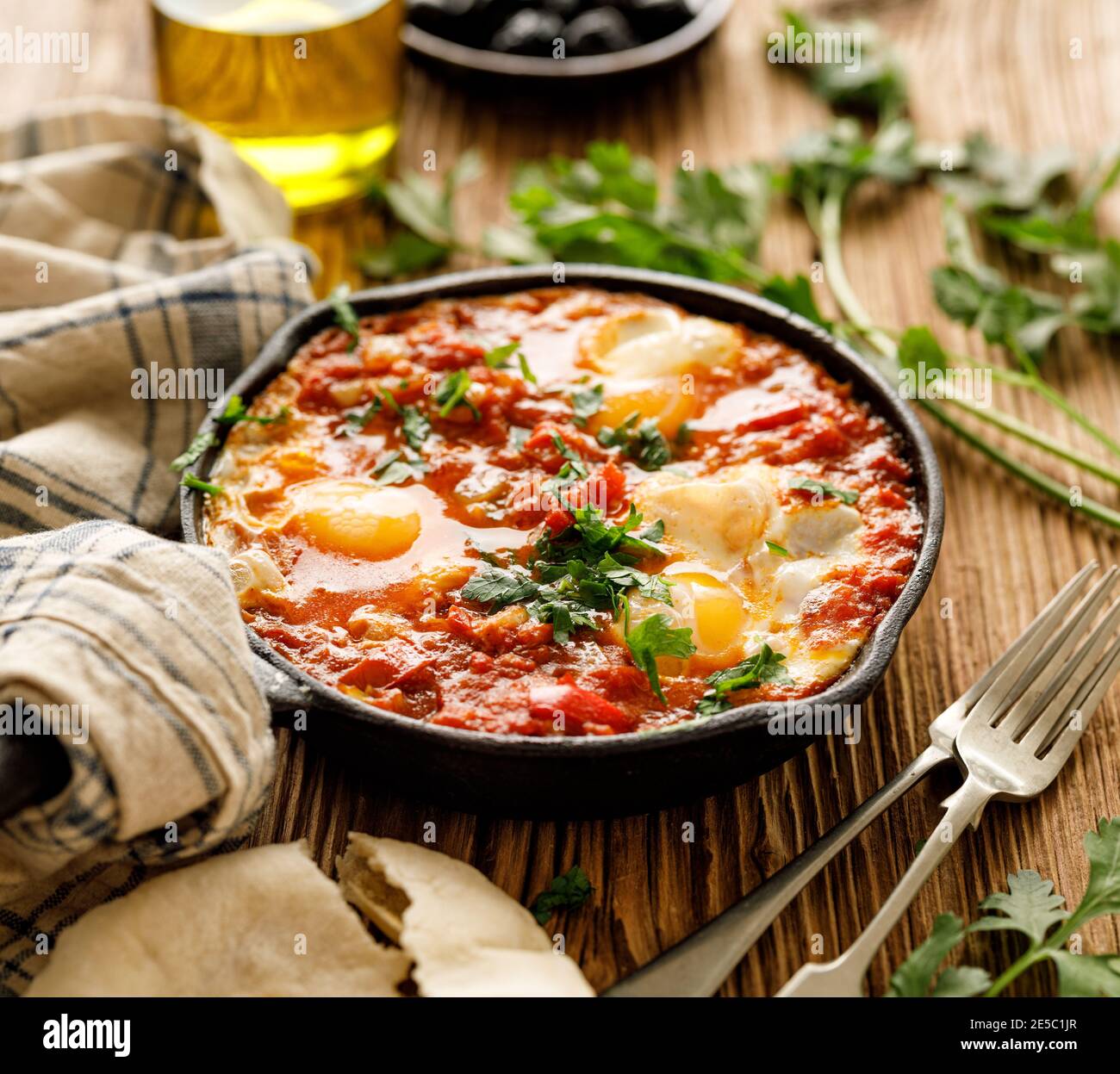 Traditional shakshuka dish served in a cast iron pan on wooden table ...