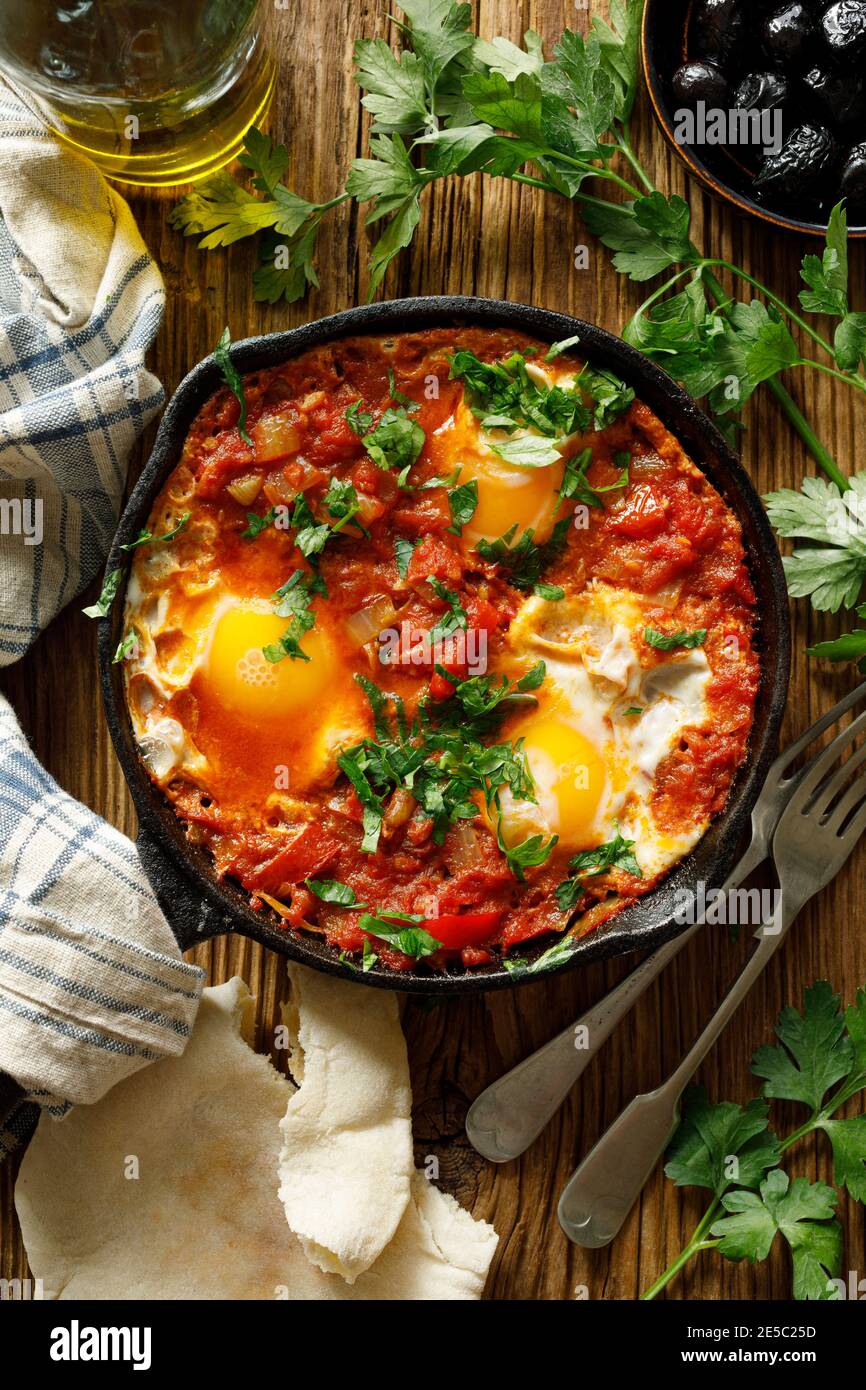 Traditional shakshuka dish served in a cast iron pan on wooden table ...
