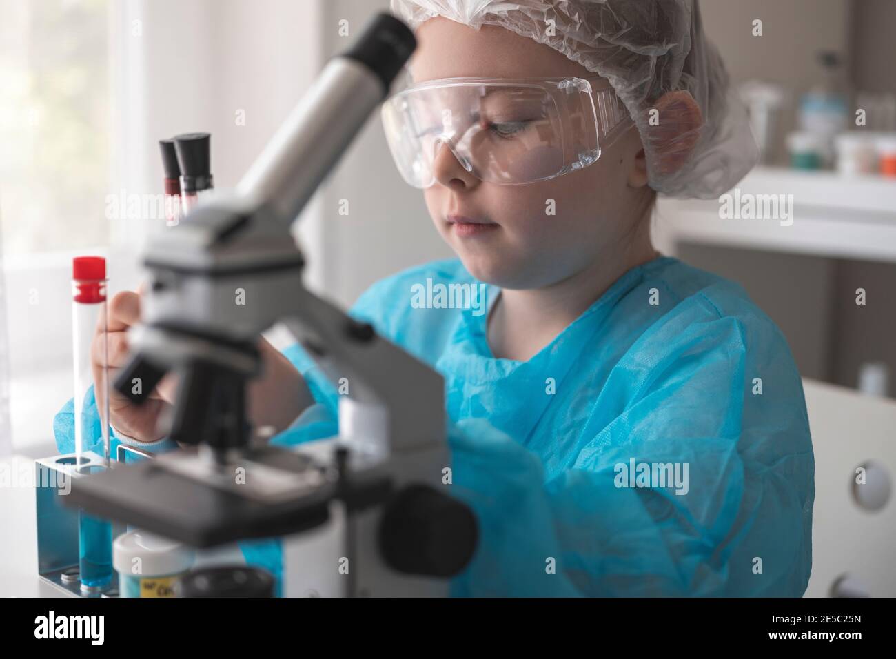 Little girl at an elementary school, using microscope research, testing ...